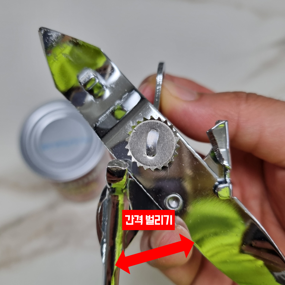 먼저 다용도 오프너의 손잡이를 벌려 통조림의 상단에 어디를 걸어야 할지를 확인합니다